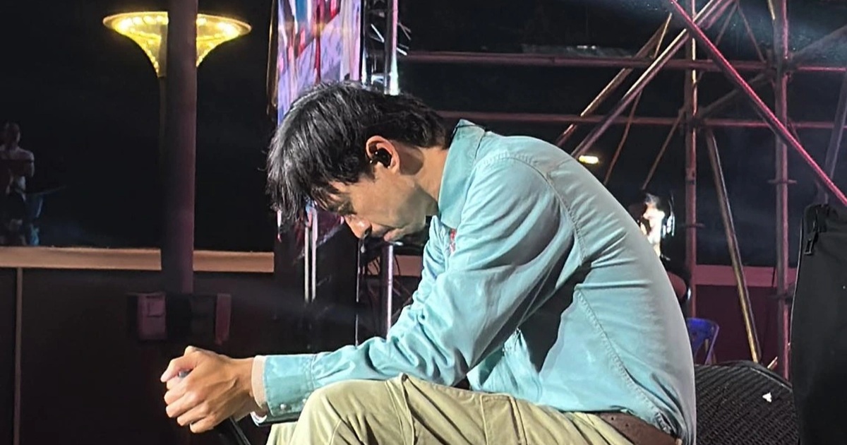 Den Vâu baixou a cabeça, perdido em pensamentos no palco em meio à ...